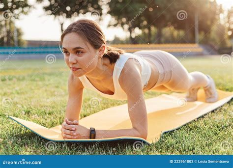 Slim Athletic Woman Wearing White Top And Beige Leggins Doing Planking