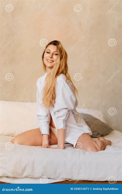 A Blond Woman In A White Shirt On Her Naked Body In Bed Stock Image