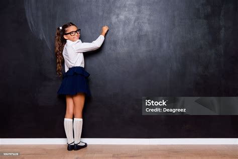 전체 크기 몸 길이 좋은 천재의 귀여운 사랑 스러운 작은 소녀 흰색 정장 블라우스 셔츠 블루 치마 곱슬 땋은 칠판에 쓰기 검은 배경 위에 절연 교육에 대한 스톡 사진 및