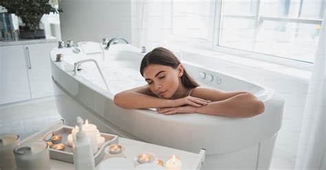 아파트에서 촛불 반대편 거품으로 물속에서 여가를 보내는 눈을 감고 있는 차분한 소녀의 초상화 사진 Unsplash의 초 이미지