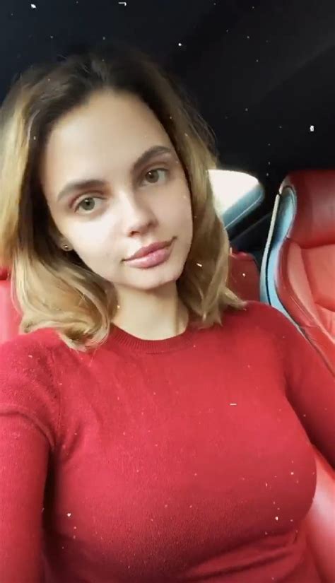 A Woman In A Red Sweater Is Sitting In A Car And Looking At The Camera