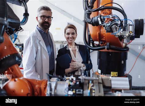 Robotics Engineers With Tablet Dicussing And Desinging Modern Robotic