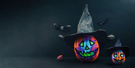 해피 할로윈 배너 검은 마녀의 모자에 피살리스와 종이로 만든 박쥐가 있는 두 개의 장식된 여러 가지 빛깔의 호박 복사 공간이 있는 어두운 배경 호박 조롱박과 식물에 대한