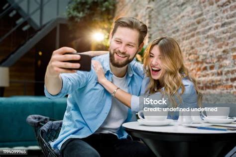 커플은 함께 시간을 즐기고 셀카를 만들고 카페 테이블에 앉아 커피를 마신다 커플 데 재미 전에 이 여행 에 대기실 2명에 대한 스톡 사진 및 기타 이미지 Istock