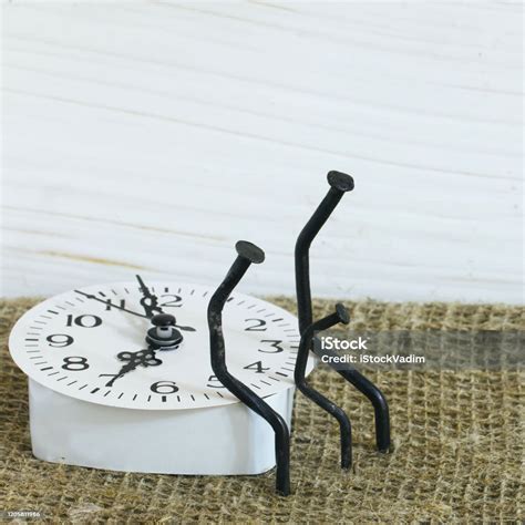 목공 손톱으로 만든 사람의 인형 그들은 시계 다이얼에 나란히 앉아 있습니다 그들 사이에 는 손톱에서 아이의 인형이 앉아있다