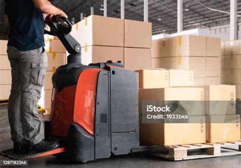 창고의 팔레트에 전기 지게차 팔레트 잭 하역 골판지 상자를 작업하는 창고 노동자 화물 선적 상자 포장 창고 보관 건축물에 대한 스톡 사진 및 기타 이미지 Istock