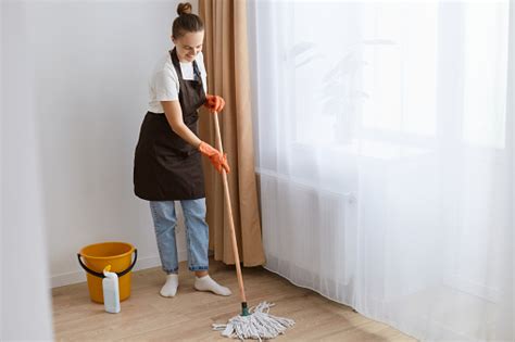 집 근처 거실에서 걸레로 바닥을 닦고 걸레를 손에 쥐고 현대 아파트에서 일하는 청소 서비스의 전장 초상화 대걸레에 대한 스톡 사진 및 기타 이미지 Istock