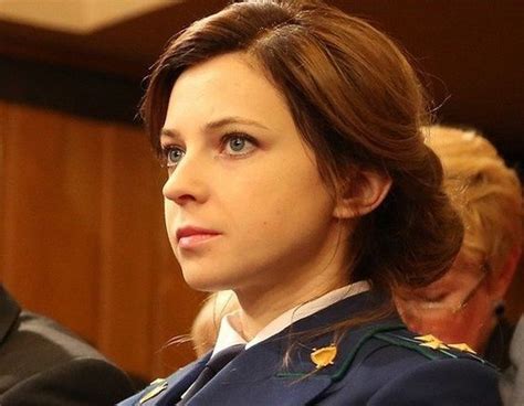 A Woman In Uniform Sitting At A Table With Other People Behind Her