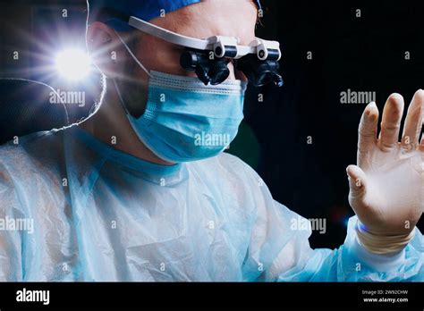 Surgeon Wearing Binocular Magnifying Glasses Operates On A Patient In A