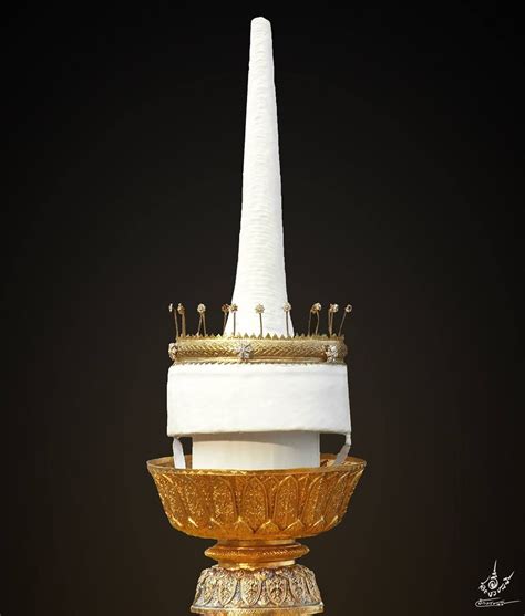 A White And Gold Cake On Top Of A Golden Pedestal With A Candle In The