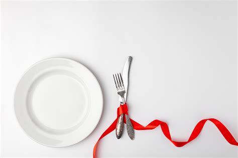 흰색 배경에 낭만적 인 축제 테이블 설정입니다 발렌타인 데이 카드 템플릿입니다 빨간 리본 접시 은제품 빈티지 포크 칼 개념 기념일 생일 텍스트 장소 카피 스페이스 상단보기