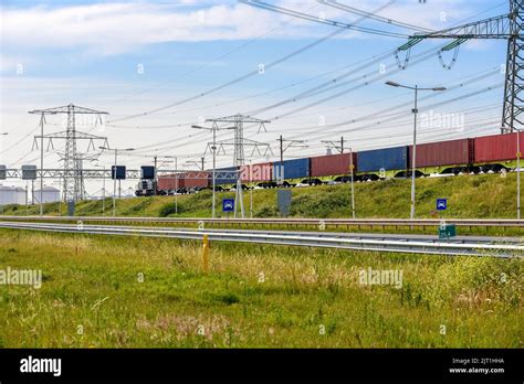 Cargo Train Loaded With Containers Running Along A Motorway In A Port