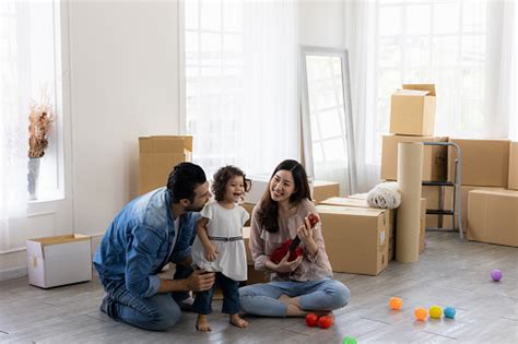 부모와 딸들은 집 안 거실 바닥에 앉아 있는 우쿨렐레와 놀고 있다 가족은 방금 새 집으로 이사했습니다 행복한 순간 다민족 아빠 엄마와 아이 가족에 대한 스톡 사진 및 기타