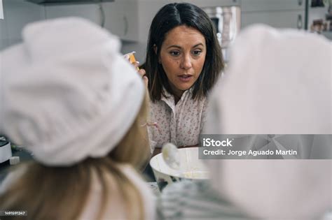 주방에서 레시피를 요리하는 방법을 설명하는 요리사 모자를 쓴 두 아이의 어머니 아이에 대한 스톡 사진 및 기타 이미지 아이 후면 숟가락 Istock