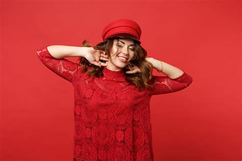 스튜디오에서 밝은 빨간색 벽 배경에 고립 된 머리에 손을 잡고 레이스 드레스와 모자에 아름 다운 웃는 젊은 여자의 초상화 사람들은 진심으로 감정 라이프 스타일 개념입니다
