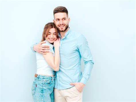 웃는 아름다운 여자와 그녀의 잘생긴 남자친구 스튜디오의 밝은 파란색 벽 근처에서 부드러운 순간을 보내는 행복한 쾌활한 가족 무료 사진