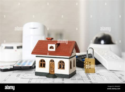 House Model Cctv Camera Lock Remote Controls Smoke And Movement Detectors On Building Plan