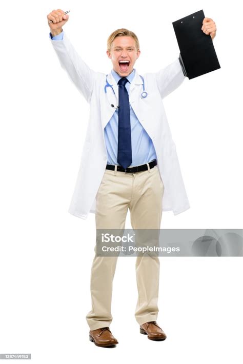 스튜디오에서 혼자 서서 축하하는 동안 클립 보드를 들고 잘 생긴 젊은 의사의 전체 길이 샷 연구실 가운에 대한 스톡 사진 및 기타 이미지 연구실 가운 의사 팔 들기