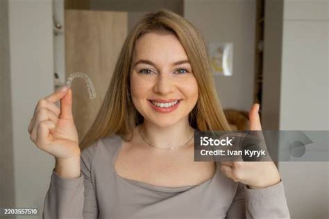 실내 환경에서 엄지 손가락을 치켜 올리고 치과 교정기를 들고 웃는 여자 25 29세에 대한 스톡 사진 및 기타 이미지 25