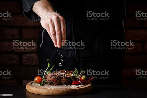 고기를 요리의 개념 요리사는 검은 색 배경에 요리 스테이크에 소금을 요리 레스토랑 메뉴에 대한 로고 아래 장소 음식 배경 이미지 복사 공간 텍스트 요리사에 대한 스톡 사진
