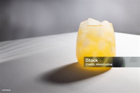 현대적인 심플한 추상적 스타일의 그라데이션 벽이 있는 흰색 테이블에 줄무늬 그림자가 있는 햇빛에 유리로 얼음을 곁들인 신선한