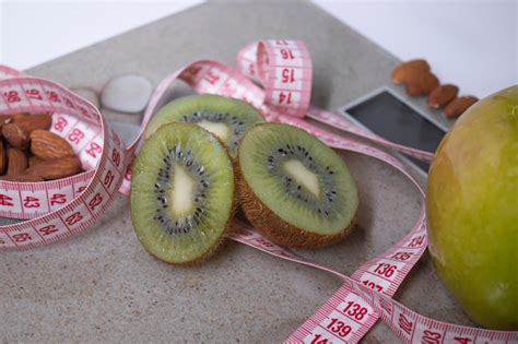 베이지 색 욕실 비늘에 빨간 측정 테이프 사과 키위와 아몬드 다이어트와 건강한 삶 체중 감량 스포츠 컨셉 맨 위 보기입니다 공간을 복사합니다 격리 흰색 배경 0명에 대한