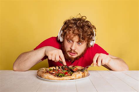 충격을 받은 붉은 수염을 가진 남자는 노란 스튜디오 배경에 고립 된 치즈와 토마토와 맛있는 피자를 자르고 먹고 25 29세에 대한 스톡 사진 및 기타 이미지 Istock