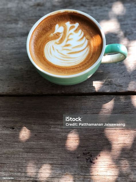 자연 채광이있는 나무 테이블에 흰색과 녹색 컵에 백조 모양 라떼 아트 커피 커피 상단보기 및 복사 공간을 사랑합니다 갈색에 대한