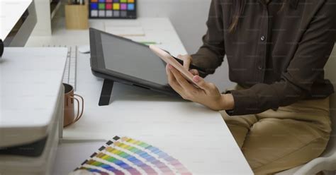 웃고 있는 여성 그래픽 디자이너가 직장에 앉아 휴대폰을 사용하여 친구들과 문자 메시지를 보내거나 마사지하는 장면을 자릅니다 사진 Unsplash의 기술 이미지