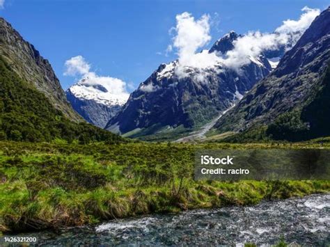 눈은 봉우리들을 덮고 뉴질랜드 밀포드 사운드로 가는 길을 따라 계곡을 매달아 놓았다 가파른에 대한 스톡 사진 및 기타 이미지