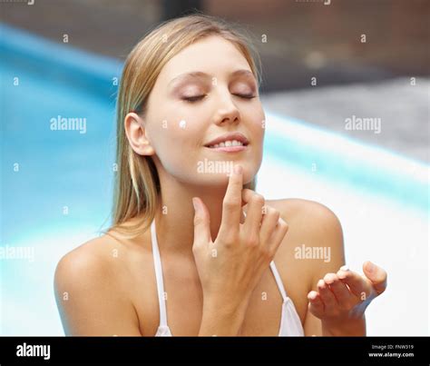 Attractive Young Woman In Pool Putting Sunscreen On Her Face Stock
