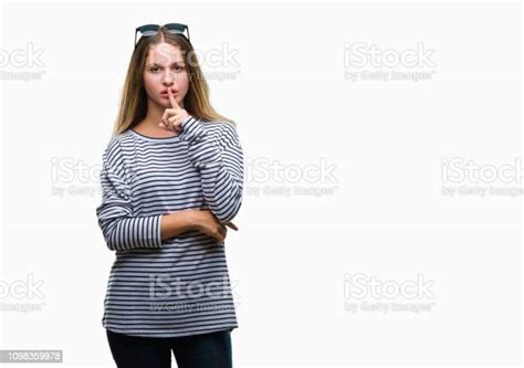 젊은 아름 다운 금발 여자 입술에 손가락으로 조용히 하 라는 고립 된 배경 위에 선글라스를 착용 침묵 그리고 비밀 개념입니다