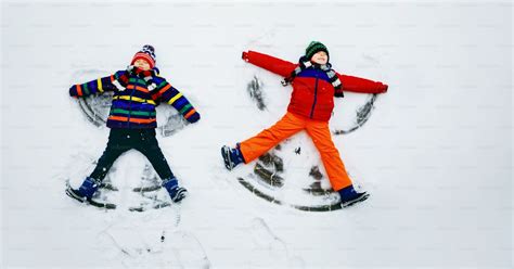 화려한 겨울 옷을 입은 두 남매가 눈 위에 누워 눈 천사를 만들고 있다 겨울에는 아이들과 함께 활발한 야외 레저를 즐길 수 있습니다 따뜻한 모자 장갑 겨울 패션을