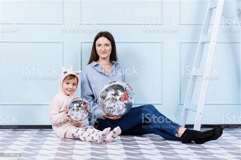 행복한 사랑의 가족 젊은 어머니와 유니콘 의상을 입은 어린 딸이 바닥에 앉아 파란색 벽 배경에 디스코 레이어를 가지고 놀고 있습니다 행복한 어머니의 날 아기의 날 2 3
