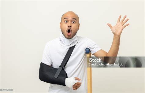 충격을 받은 얼굴 아시아 남자는 고립된 팔과 다리를 부러뜨렸다 남자는 지팡이 목발로 석고 캐스트 부목을 착용했습니다 목 칼라가 있는 슬링 지지 팔을 착용한 환자 생명 보험