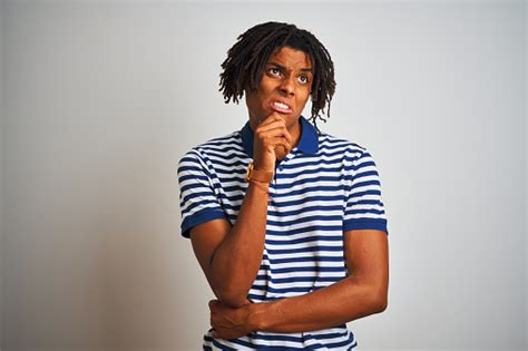 고립 된 흰색 배경 위에 서있는 줄무늬 파란색 폴로를 입은 공포를 가진 아프로 남자 걱정과 턱에 손으로 긴장 질문에 대해 생각 감정에 대한 스톡 사진 및 기타 이미지