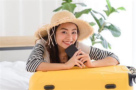여름 캐주얼 옷과 밀짚 모자에 젊은 아시아 여성의 초상화는 침실에서 노란색 수하물과 미소와 편안한 분위기 그것은 여름 시간에