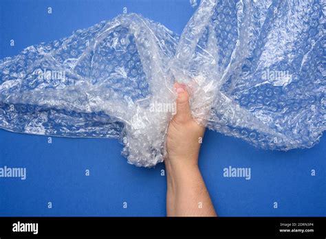Female Hand Holding Crumpled Piece Of Polyethylene With Air Bubbles On
