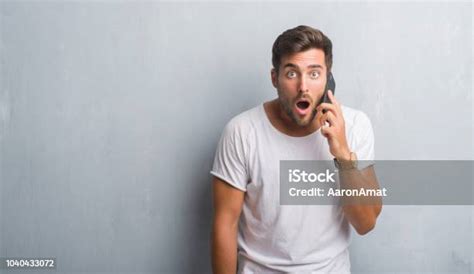 놀라운 얼굴 두려워 하 고 공포 식으로 흥분 충격에서 무서 워 전화에 말하는 회색 그런 지 벽에 잘생긴 젊은 남자 감정에 대한 스톡 사진 및 기타 이미지 Istock