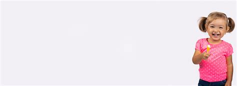 배너 긴 형식 행복하고 진지한 미소 포니 테일과 그녀의 손에 롤리팝과 작고 달콤하고 아름다운 소녀 빈 측면 공간이있는 흰색 배경에 사진 고여 있는 물에 대한 스톡 사진 및