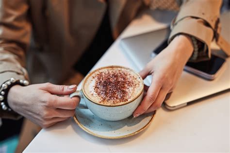 위에는 커피 컵을 가진 손과 여자가 휴식을 취하고 카카오가 고객 여가 휴식과 향기로 뿌려집니다 사람 평면도 및 머그잔 아침 음료 및 카페에서 카푸치노와 함께 고객 근접 촬영