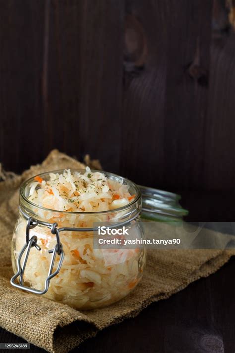 검은 색 배경에 유리 항아리에 허브와 당근과 수제 소금에 절인 양배추 나무 테이블에 자루가 있는 양배추절임 복사 공간을 복사합니다 통조림 식품의 개념 채식 음식 수직 0명에