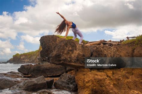 젊고 매력적이 고 집중 된 여 자가 건강 한 자연 라이프 스타일에서 아름 다운 해변 바위 절벽에서 Acroyoga 균형 운동과
