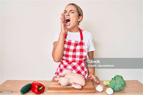 젊은 아름다운 금발 여자 에이프런 요리 치킨 소리와 입에 손으로 옆으로 큰 소리로 비명을 입고 통신 개념 부엌에 대한 스톡 사진 및 기타 이미지 Istock