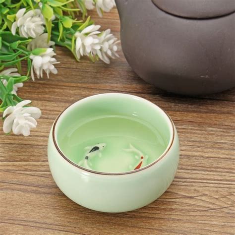 the bowl is filled with green liquid and sits on a table next to white ...