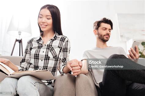 아름다운 미소 짓는 여인이 의자에 앉아 책을 읽으며 집 근처에서 젊은 남자와 손을 잡고있는 초상화 25 29세에 대한 스톡 사진 및 기타 이미지 Istock