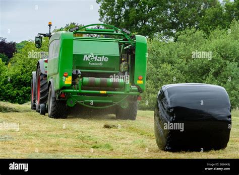 Hay Or Silage Making Farmer In Farm Tractor At Work In Rural Field