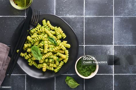 페스토와 이탈리아 푸실리 파스타 검은 돌 조리대 배경에 검은 접시에 바질 페스토와 허브 파르 메산 치즈 바질 및 마늘을 곁들인 Fusilli 파스타 상단 보기 공간을