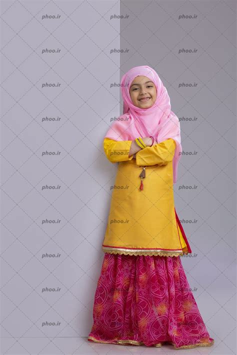 عکس دختر بچه خندان ایستاده با لباس سنتی با زمینه طوسی عکس با کیفیت و