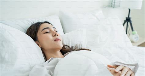 잠옷을 입은 아시아의 아름다운 위안 소녀는 침실에서 잠에서 일어난다 침대에 누워 있는 매력적인 젊은 여성은 아늑한 베개와 담요로 행복을 느끼고 집에서 방에서 일어난 후